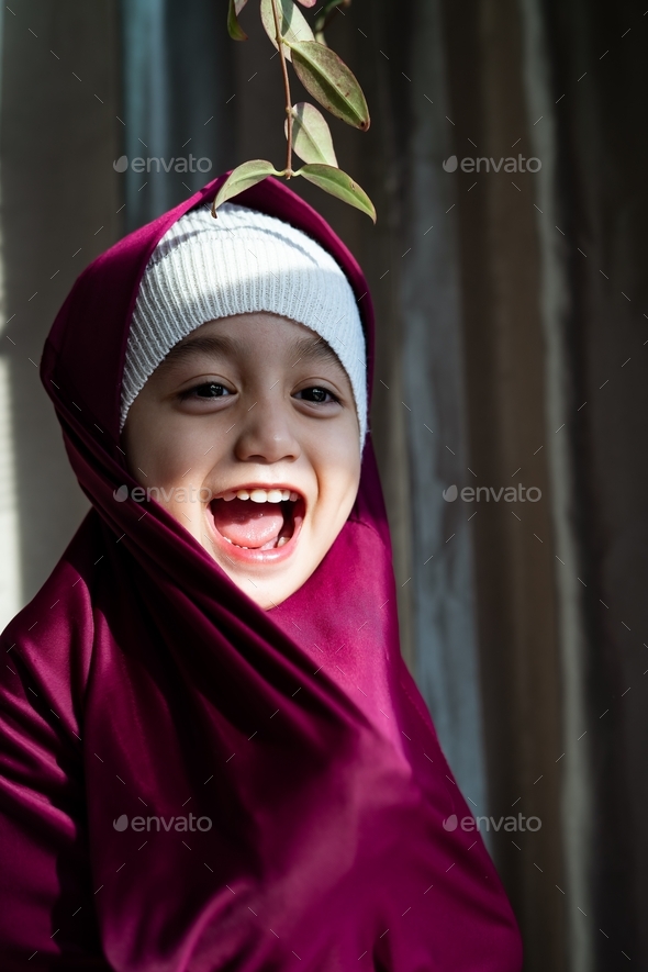 Portrait of a Muslim toddler kid wearing hijab with dapple lights on ...