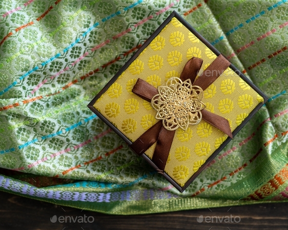Yellow gift boxes with golden brooch. Traditional songket on one of the ...