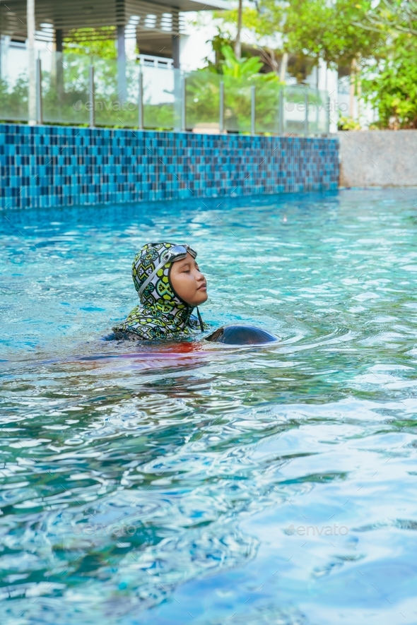 Young girl wearing hijab and Muslim swimming wear in the pool. Happy ...