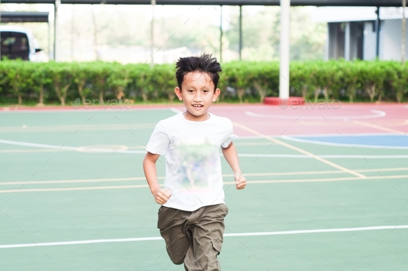 young asian boy running in the basketball court Stock Photo by ellinnur