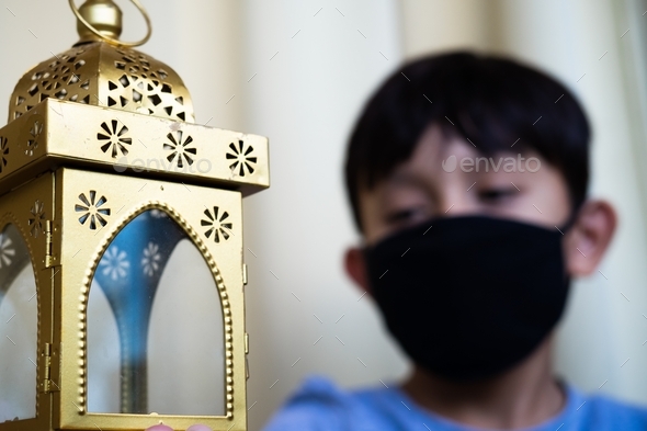 islamic design gold lantern with boy wearing face mask in the ...