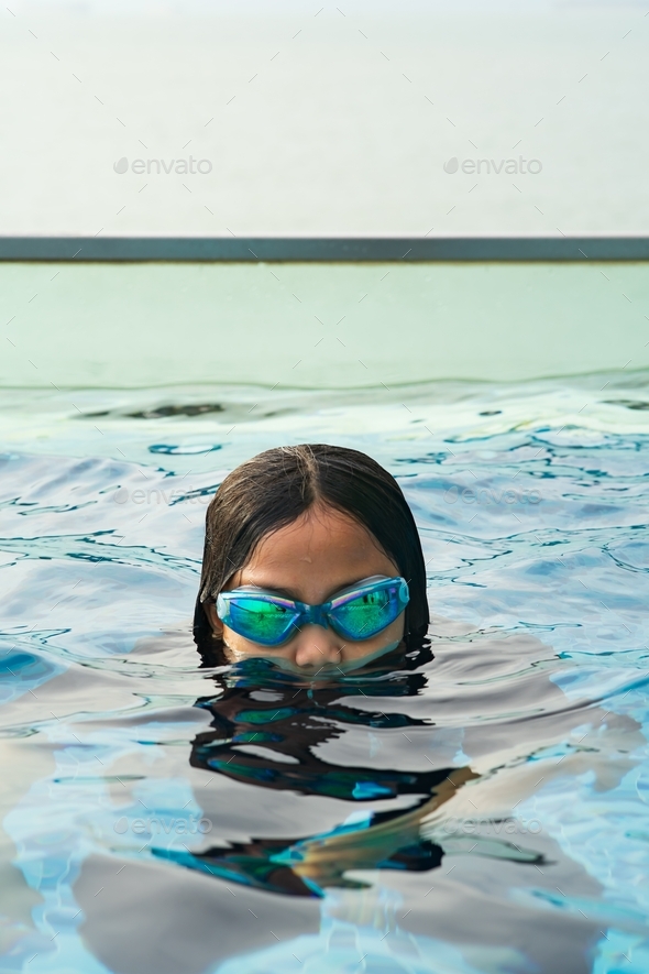 Young child in the pool. Kid having fun in swimming pool. Wearing ...