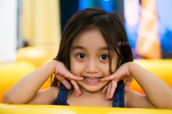 Close up of little asian girl, looking in camera with cute expression ...