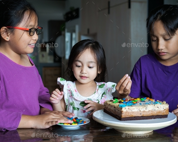 children decorating birthday cake together at home Stock Photo by ellinnur