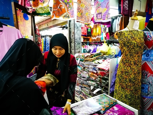 seller at Malaysian bazaar selling traditional batik, hand drawing fabrics Stock Photo by ellinnur