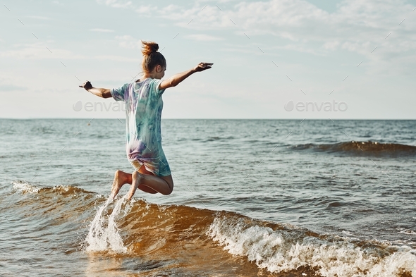 Girl enjoying sea jumping over waves spending a free time over sea on a ...