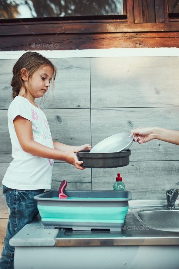 Teenager girl washing up the dishes pots and plates with help her ...