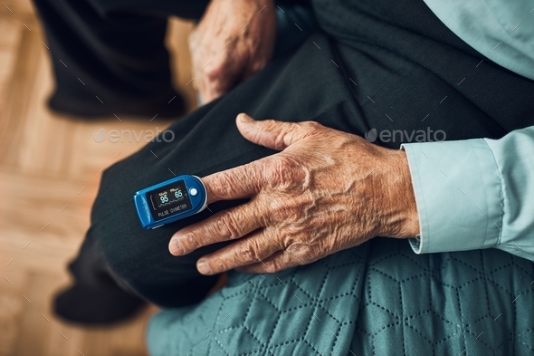 Senior man measuring the degree of oxygen saturation of the blood at ...