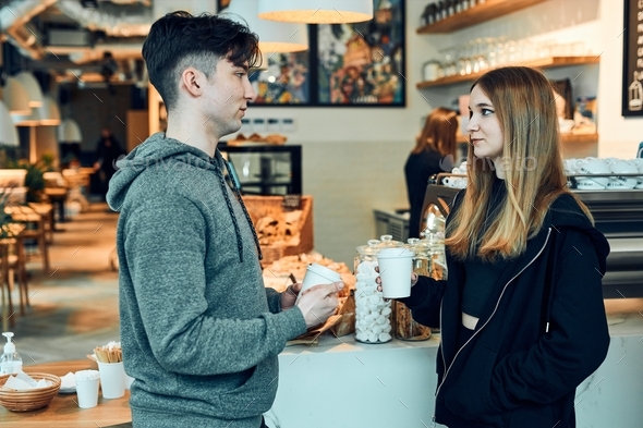 Coffee break. Friends having a chat, holding coffee cups, standing in a ...