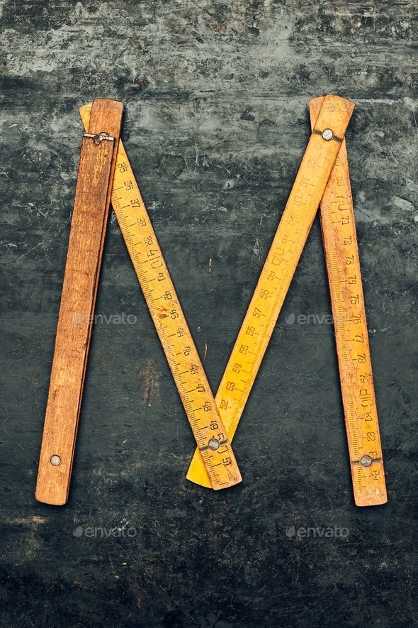 M like measuring. Wooden measure. Old ruler on metal surface. Measuring ...
