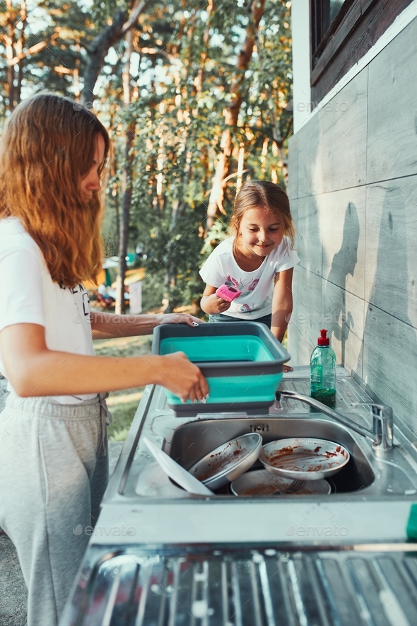 Teenager girl washing up the dishes pots and plates with help her ...