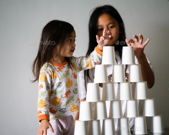 two children playing stacked paper cups together at home Stock Photo by ...