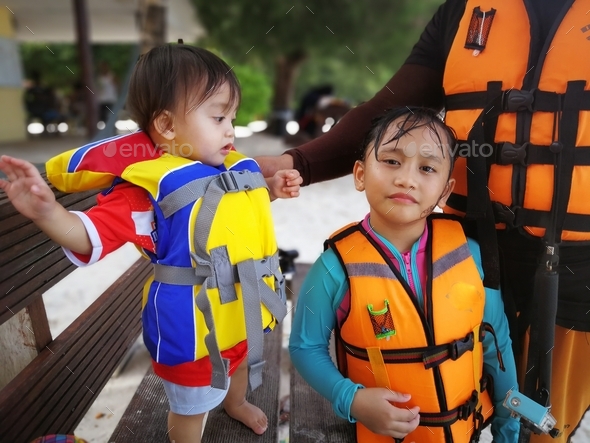 children wearing life jackets at the beach Stock Photo by ellinnur