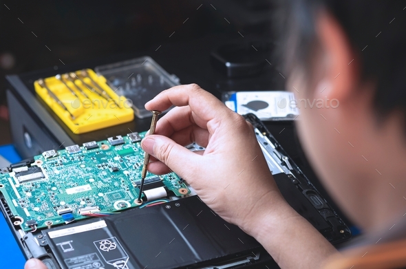 Focus at technician hand is assembling the motherboard of laptop ...