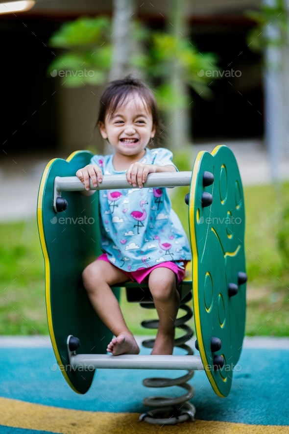 toddler girl on the bouncy ride smiling happily Stock Photo by ellinnur