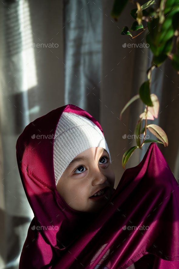 Portrait of a Muslim toddler kid wearing hijab with dapple lights on ...