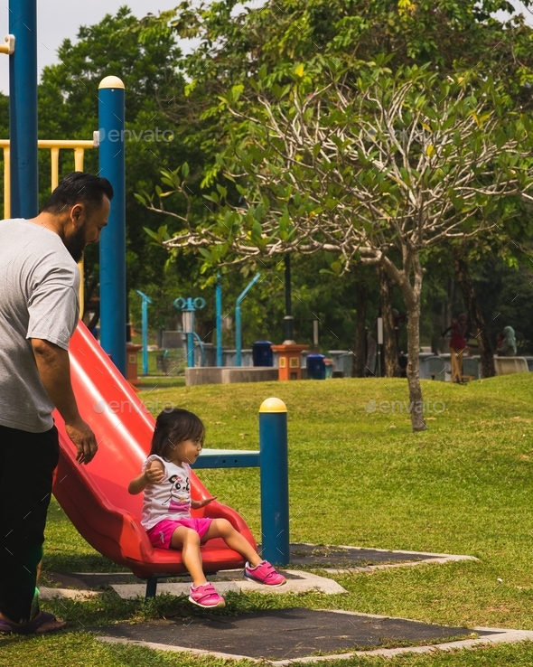 Little girl playing slides at the playground with her father. Stock ...