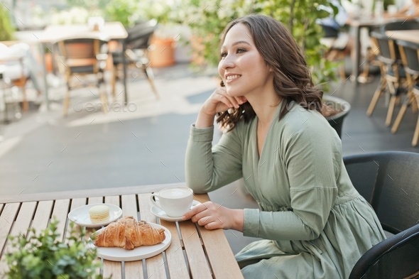 Millennial woman eating french breakfast with coffee at the terrace of ...