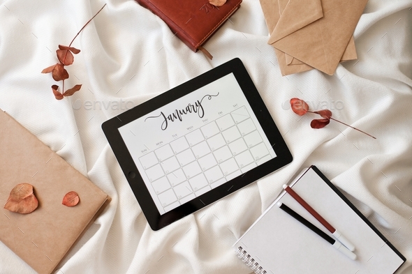Calendar flat lay with a tablet and January month page on the white ...