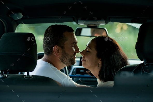 Beautiful couple in love man and woman inside car driving on road trip ...