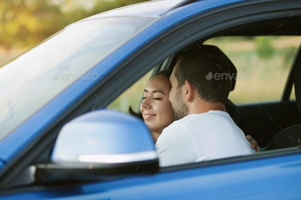 Beautiful couple in love man and woman inside car driving on road trip ...