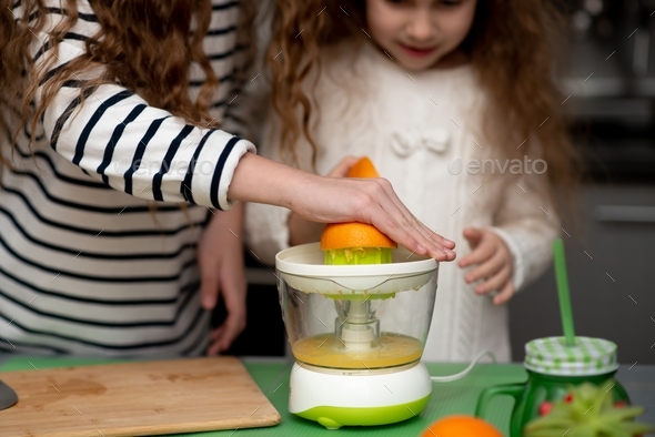 Two cute girls make an orange fresh. Hands close-up. Healthy eating ...