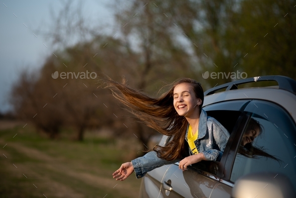 A teenage girl looks out of the car window. Journey. Sunset. Beauty ...