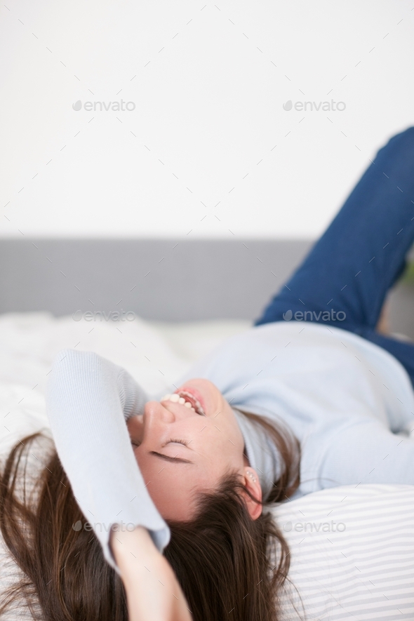 Woman lying on the bed smiling and laughing, positive vibes, at home ...