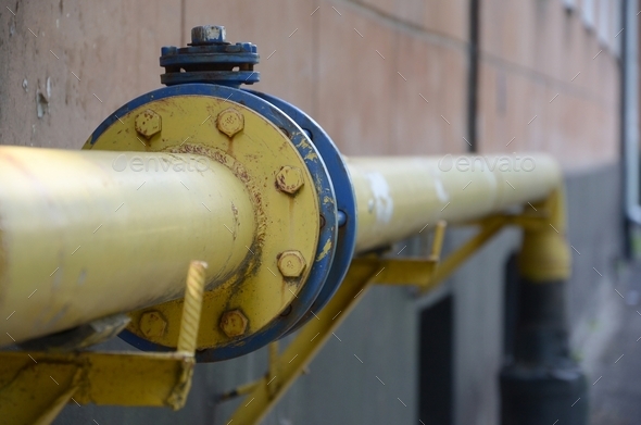 Yellow gas pipe in front of residential building wall. Stone wall ...