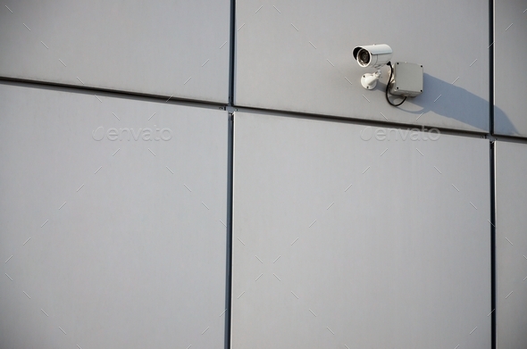 White surveillance camera built into the metal wall of the office ...