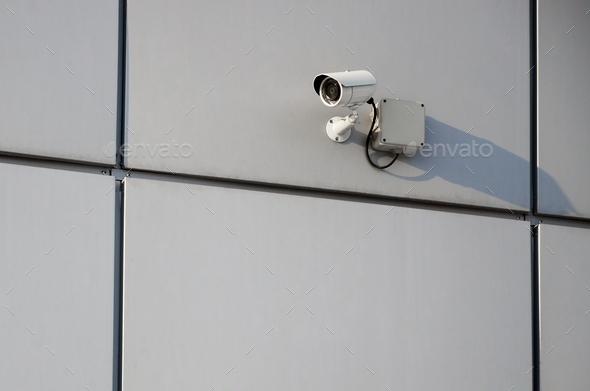 White surveillance camera built into the metal wall of the office ...