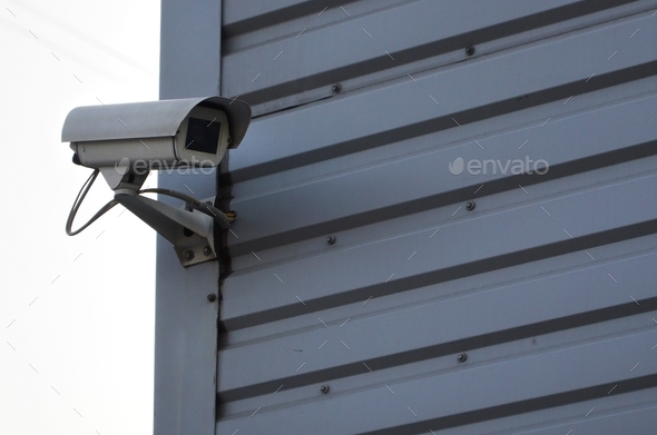 White surveillance camera built into the metal wall of the office ...