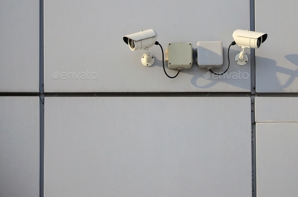 White surveillance camera built into the metal wall of the office ...