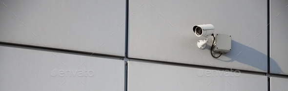 White surveillance camera built into the metal wall of the office ...