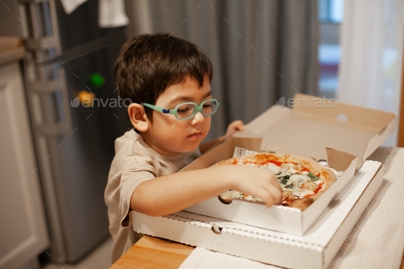 kid taking pizza from the box before eating, pizza night, little boy of ...