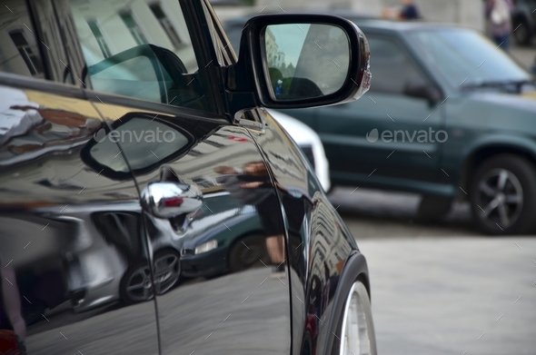 Diagonal view of a black glossy car with white wheels, which stands on ...