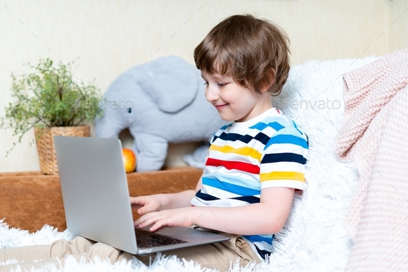 Child kid boy typing at laptop computer home. Watching movie, using ...
