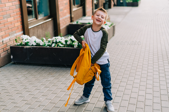 Back to school. Happy child packing backpack, holding notepad and ...
