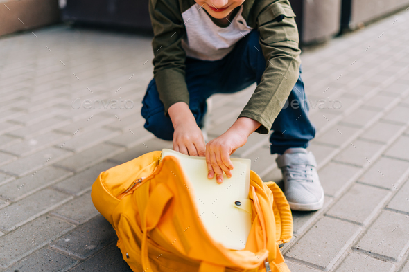 Back to school. Cute child packing backpack, holding notepad and ...