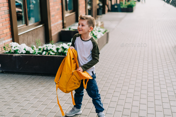 Back to school. Cute child packing backpack, holding notepad and ...