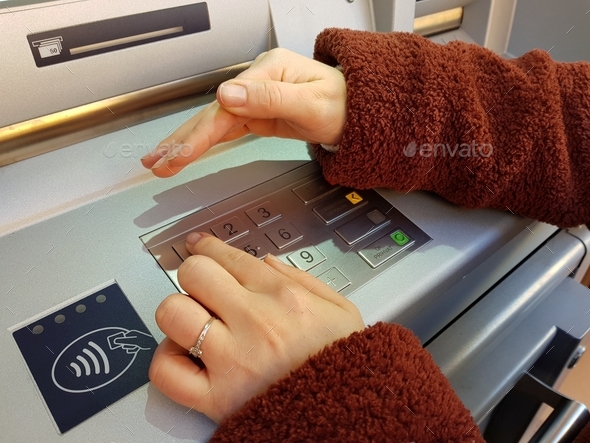 Close-up cropped image of woman withdrawing money on atm. Entering pin ...