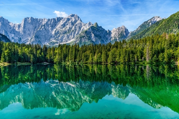 Spectacular green alpine lake surrounded by forest and mountains ...