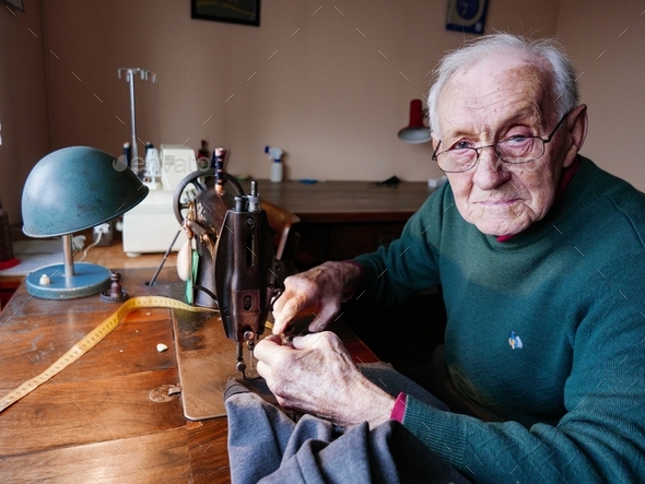 Old man working behind a sewing machine. Stock Photo by 9_fingers_
