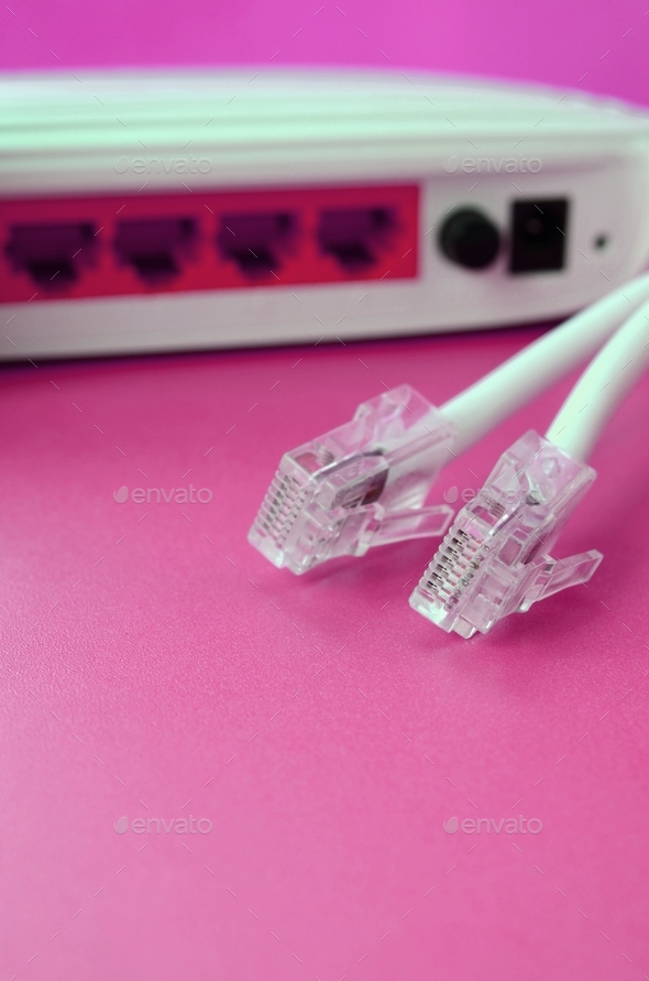 Internet router and Internet cable plugs lie on a bright pink ...