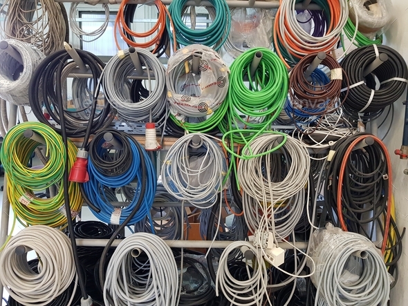 Electrical wires and cables hanging on rack on wall in factory. Stock ...