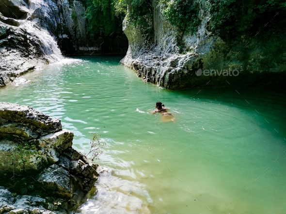 Woman swimming in natural green river pool under small waterfall Stock ...
