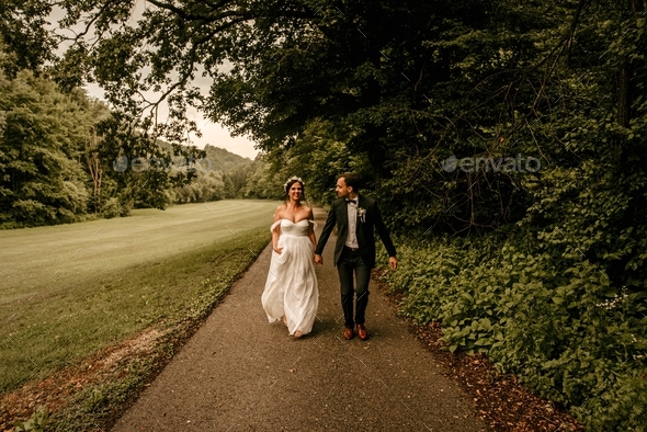 Front view of bride and room walking down a path in forest. Stock Photo ...