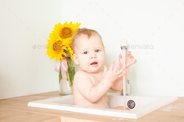 Baby taking bath in kitchen sink. Little boy bathing. Water fun for ...
