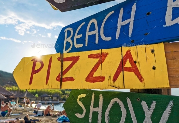 Colorful wooden signs on sign post at beach. Stock Photo by 9_fingers_