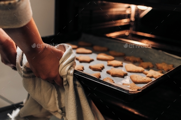 Close-up photo of woman taking baking tray with christmas cookies out ...